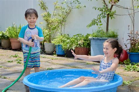 Brother And Sister Playing In A Shallow Pool In The Backyard Stock Image Image Of Pool