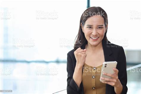 자신감 넘치는 젊은 아시아 사업가들이 현대적인 사무실 건물과 도시 배경에서 비즈니스 미팅에서 스마트폰을 사용하면서 행복한 웃는