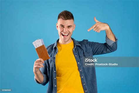 파란 배경에 여권과 비행기 티켓을 가리키는 흥분 밀레니엄 남자 남자에 대한 스톡 사진 및 기타 이미지 남자 비행기 티켓 여행 개념 Istock