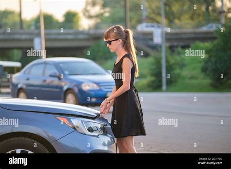 Female Driver Opening Car Hood Inspecting Broken Engine On A City