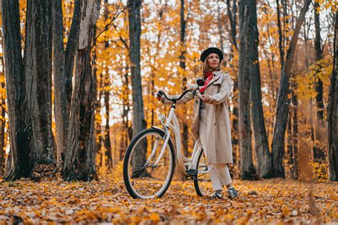 노란 가을 공원에서 복고풍 자전거와 고전적인 트렌치 코트를 입은 젊은 여성 자연 배경에 트렌디 한 소녀의 놀라운 장면 환경 친화적인 교통 수단 가을에 대한 스톡 사진 및