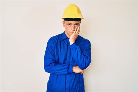 노동자 유니폼과 하드 햇을 입고 젊은 히스패닉 소년은 지치고 교차 팔에 우울증 문제로 지루해 찾고 생각 건설업자에 대한 스톡 사진 및 기타 이미지 Istock