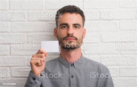 빈 카드 스마트 얼굴 심각한 생각에 자신감을 표현 하는 벽돌 벽을 통해 젊은 성인 남자 감정에 대한 스톡 사진 및 기타 이미지
