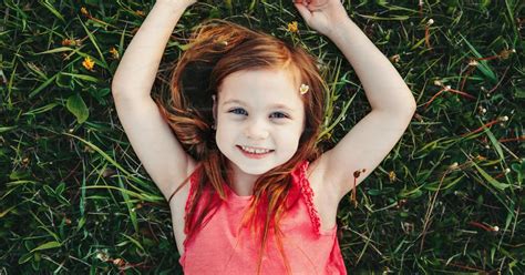 귀여운 웃는 백인 소녀가 초원의 풀밭에서 쉬고 있다 아이가 땅에 누워 있습니다 야외 활동 재미 여름 어린이 활동 밖에서 즐거운 시간을 보내는 아이 행복한 어린 시절