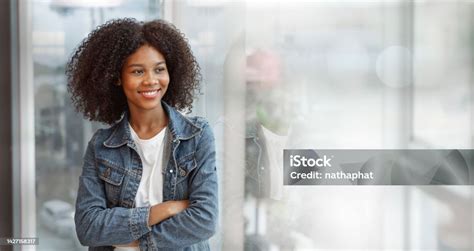 사무실에서 창문 옆에 서서 웃고있는 푸른 청바지를 입은 매력적인 젊은 아프리카 사업가의 초상화 서 있기에 대한 스톡 사진 및 기타 이미지 Istock