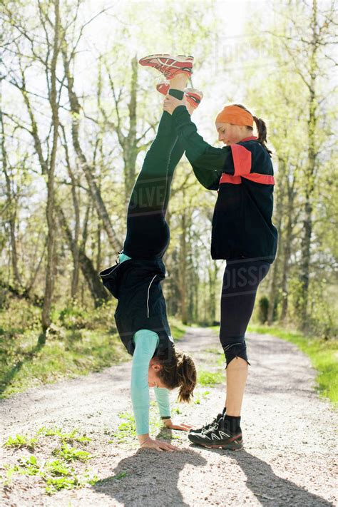 Woman Helping Sister Doing Handstand On Road Stock Photo Dissolve