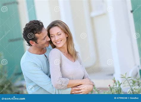 Loving Middle Aged Couple Embracing In Front Their New Home Stock Photo