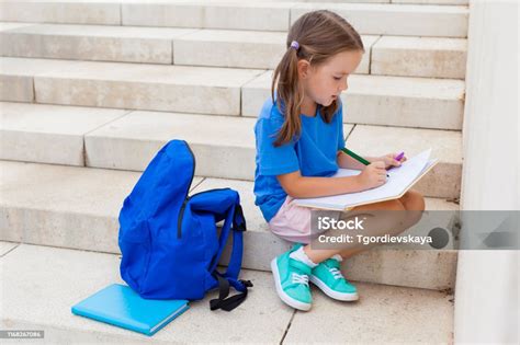 학교 의 첫날 개념다시 학교에 학교 근처 계단에 앉아 있는 여학생 초등학생이 노트북을 그립니다 손에 책을 가진 학생 교육에 대한