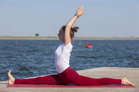Young Girl Practices Yoga On The Shore Of The Lake The Concept Of