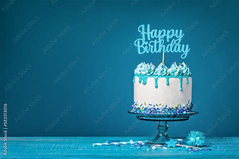 White Happy Birthday Cake With Teal Ganache Over A Blue Background