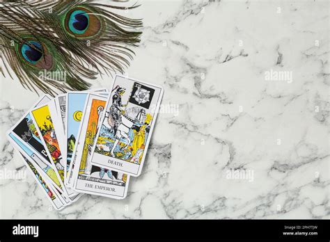 Tarot Cards And Peacock Feathers On White Marble Table Flat Lay Space