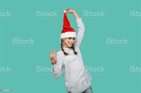 새 해 개념입니다 행복 한 재미 있는 아름 다운 소녀 줄무늬 밝은 파란색 셔츠 서 및 빨간 크리스마스 모자를 들고 승리 또는