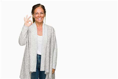 아름 다운 중 년 성인 여자 격리 된 배경 손과 손가락으로 Ok 사인을 하 고 긍정적인 미소를 통해 겨울 스웨터를 입고 성공적인 식입니다 가을에 대한 스톡 사진 및 기타