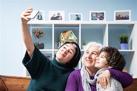 거실에서 그녀의 수석 어머니와 일곱 살 짜리 아들과 함께 셀카를 찍는 중반 성인 여성 40 49세에 대한 스톡 사진 및 기타 이미지 40 49세 6 7 살 가정 생활