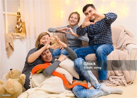 집에서 소파에 앉아 있는 가족의 초상화 네 사람이 함께 즐거운 시간을 보내고 손으로 하트 모양을 보여주는 사진 4 명에 대한 스톡 사진 및 기타 이미지 Istock