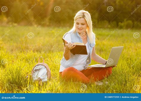 Portrait Of Pretty Young Woman Sitting On Green Grass In Park With Legs