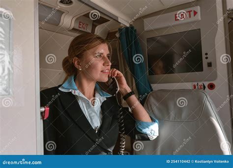 Professional Stewardess Talking On Telephone In Airplane Cabin Stock