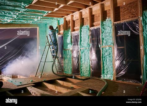 Male Builder Insulating Wooden Frame House Man Worker Spraying