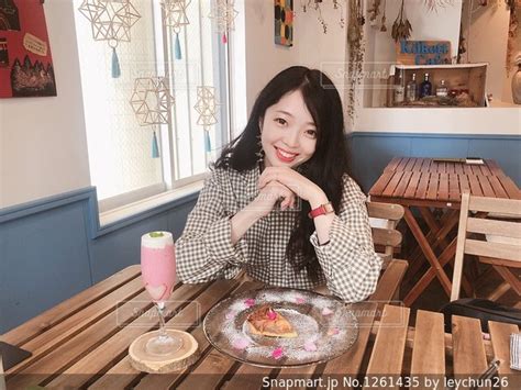 カメラにポーズのテーブルに座っている女性の写真・画像素材 Snapmart（スナップマート）