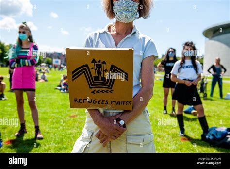 A Woman Is Holding A Placard In Support Of The Refugees While Wearing A