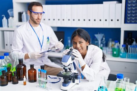 Man And Woman Scientists Using Microscope Working At Laboratory Stock
