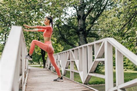 Fit Slim Girl Stretching Her Legs While Standing On A Bridge In The
