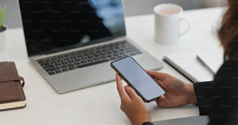 작업 책상에서 빈 화면 모바일을 손에 들고 있는 동안 사업가의 잘린 사진 검은색 빈 스크린 노트북 노트북 커피 컵 작업 책상에 있는 문서 사진 Unsplash의