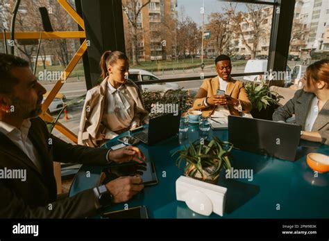 Group Of Four Business People Talking While Sitting At The Cafe Stock