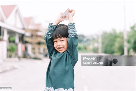 귀여운 말레이 소녀 말레이 전통 천은 이드 피트리 축하 행사에서 돈 주머니를받은 후 행복한 반응을 보여줍니다 2 3 살에 대한
