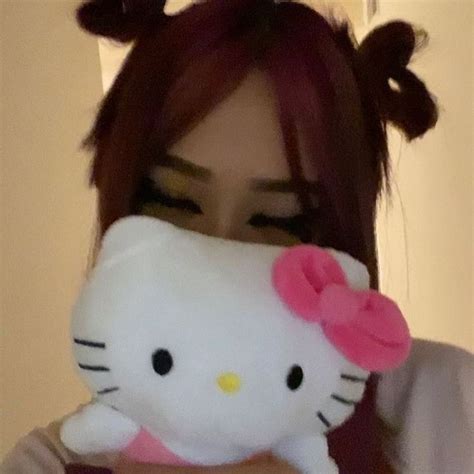 A Woman Holding A Hello Kitty Stuffed Animal In Front Of Her Face And