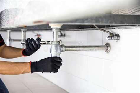 Technician Plumber Using A Wrench To Repair A Water Pipe Under The Sink