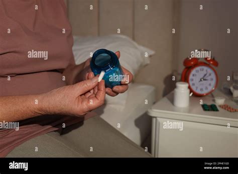 Elderly Woman Suffering From Insomnia Taking Pill On Bed At Night