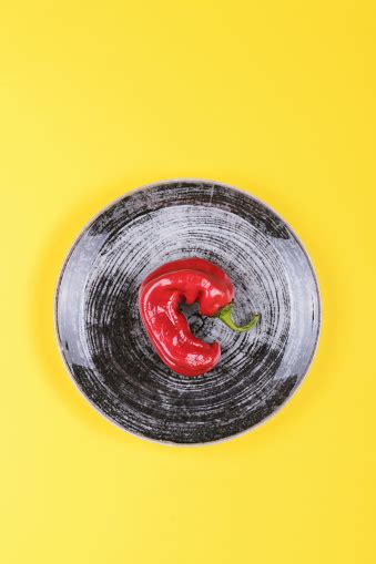 노란색 배경에 검은 접시에 못생긴 붉은 칠리 고추 자연의 최소한의 스타일 팝 아트 창조적 인 음식 개념 현대 미술 개념에 대한