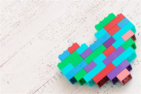 소년의 색 구성표의 여러 가지 색깔의 큐브로 만든 마음의 클로즈업 어린이 교육 장난감 다채로운 큐브 벽돌 및 흰색 나무 배경의