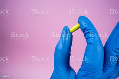 분홍색 배경이있는 손바닥에 노란색 약약을 들고있는 파란색 라텍스 장갑을 가진 손 0명에 대한 스톡 사진 및 기타 이미지 0명