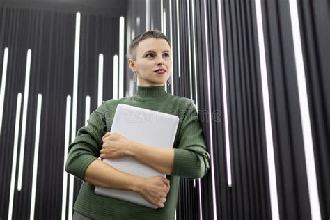 Mature Woman Website Developer With A Laptop In Her Hands Against A Black Wall Stock Image