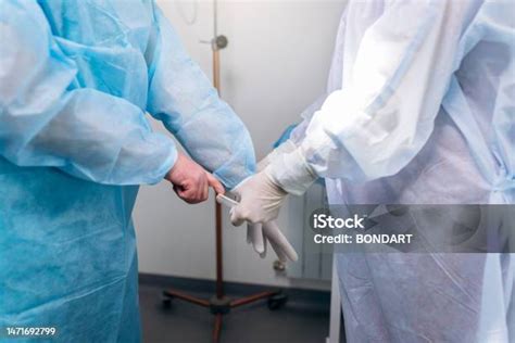 수술 전에 외과의에게 의료용 장갑을 끼고 있는 간호사의 클로즈업 의사는 수술실에서 수술을 준비하고 의료 유니폼을 입습니다 2명에 대한 스톡 사진 및 기타 이미지 Istock
