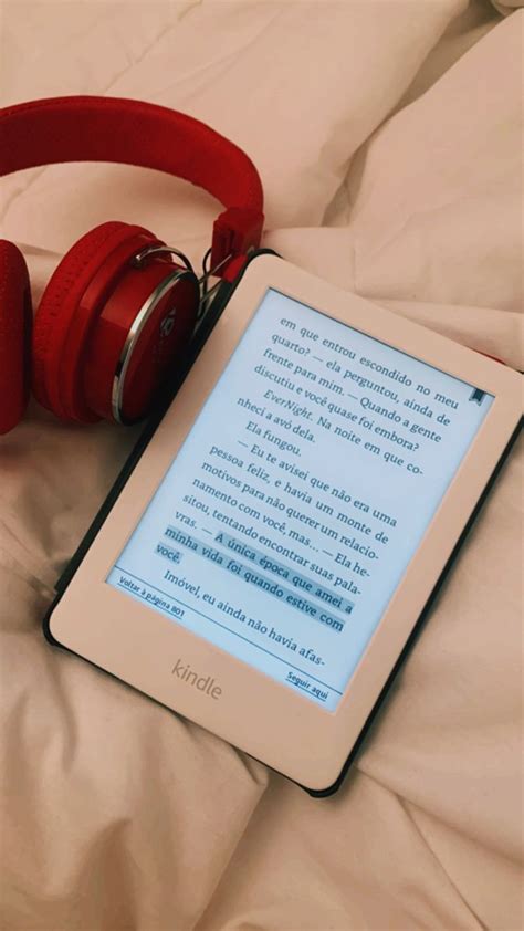 An Electronic Device Sitting On Top Of A Bed Next To Headphones And A Book