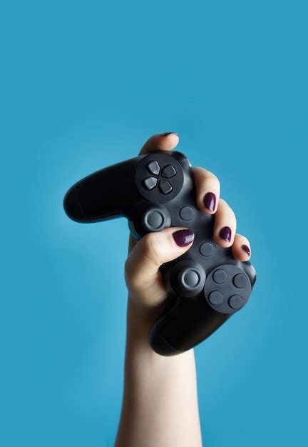 A Female Hand Holds A Controller From A Video Console On A Blue