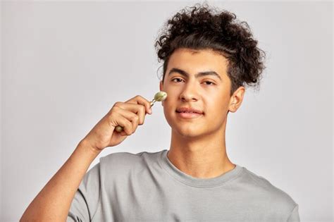 Premium Photo Young Handsome Smiling Guy Using Jade Depuffing Face