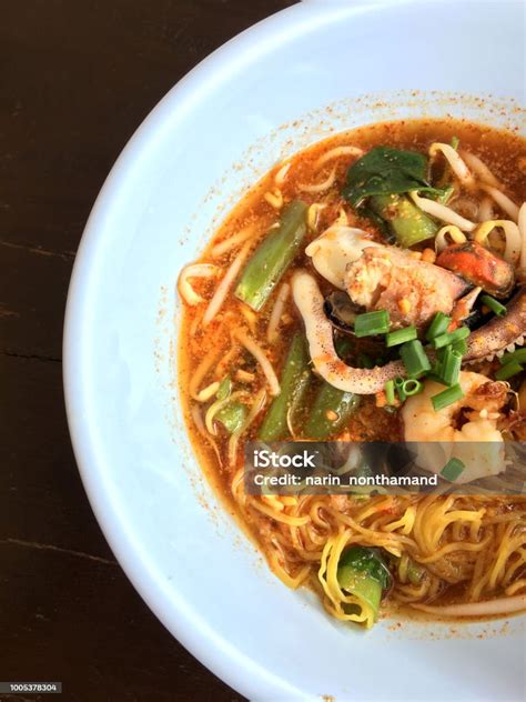 새우 오징어 나무 테이블 Tom Yum Goong에 흰색 그릇에 조개와 맛 있는 아시아 매운 해산물 국수 수프 태국 스타일