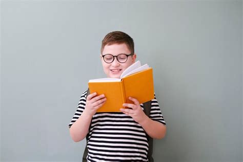 Un lindo chico alegre con camiseta desnuda con vidrio y está leyendo un