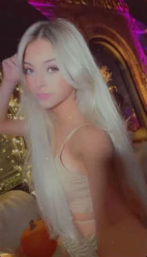 A Woman With Long White Hair Posing In Front Of A Christmas Tree