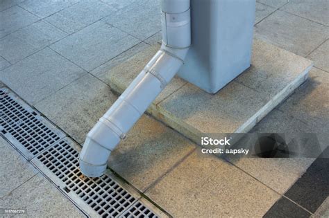 끝에 배수 파이프 용 신발이있는 금속 배수 파이프 금속 콘크리트 지지대에 고정 그랜트 슬래브에 검은 금속 사각형 거터 화격자로 이어집니다 물에 대한 스톡 사진 및 기타