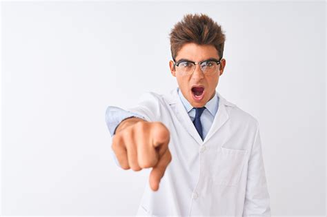 젊은 잘 생긴 Sciencist 남자 안경과 코트를 입고 고립 된 흰색 배경 을 가리키는 불쾌하고 카메라에 좌절 당신과 함께