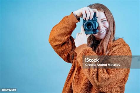 파란 바탕에 카메라를 들고 있는 한 젊은 여성이 우리를 마주보고 서 있는 사진을 찍고 있다 20 24세에 대한 스톡 사진 및 기타 이미지 20 24세 감정 몸 가꾸기