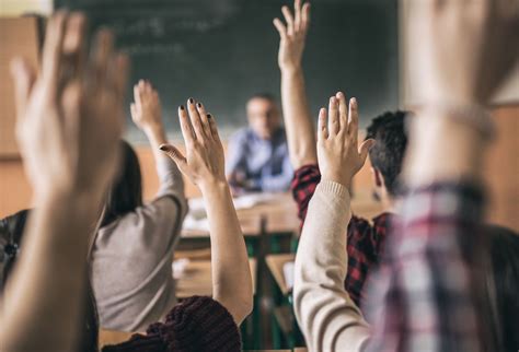 High School Students In Classroom Raising Hands