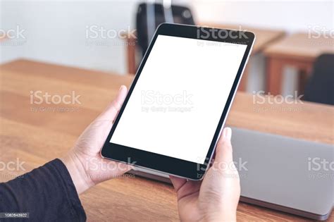 손 들고 나무 테이블 사무실에서 노트북으로 빈 흰색 바탕 화면으로 검은 Tablet Pc를 사용 하 여의 이랑 이미지 공란에
