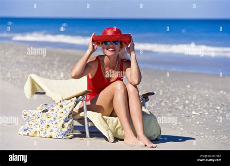 ans Femme à la plage en maillot de bain assis dans la chaise de plage bronzage South