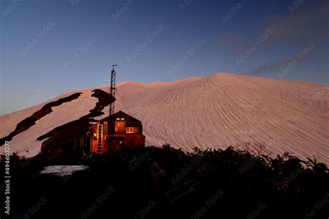 残雪の越後駒ヶ岳山頂のモルゲンロートと駒の小屋 Stock Photo Adobe Stock